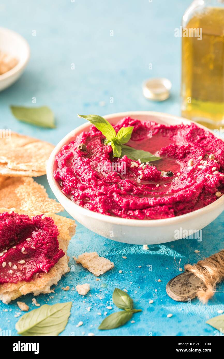 red beetroot hummus on blue background, lemon, sesame, olive oil, pita ...