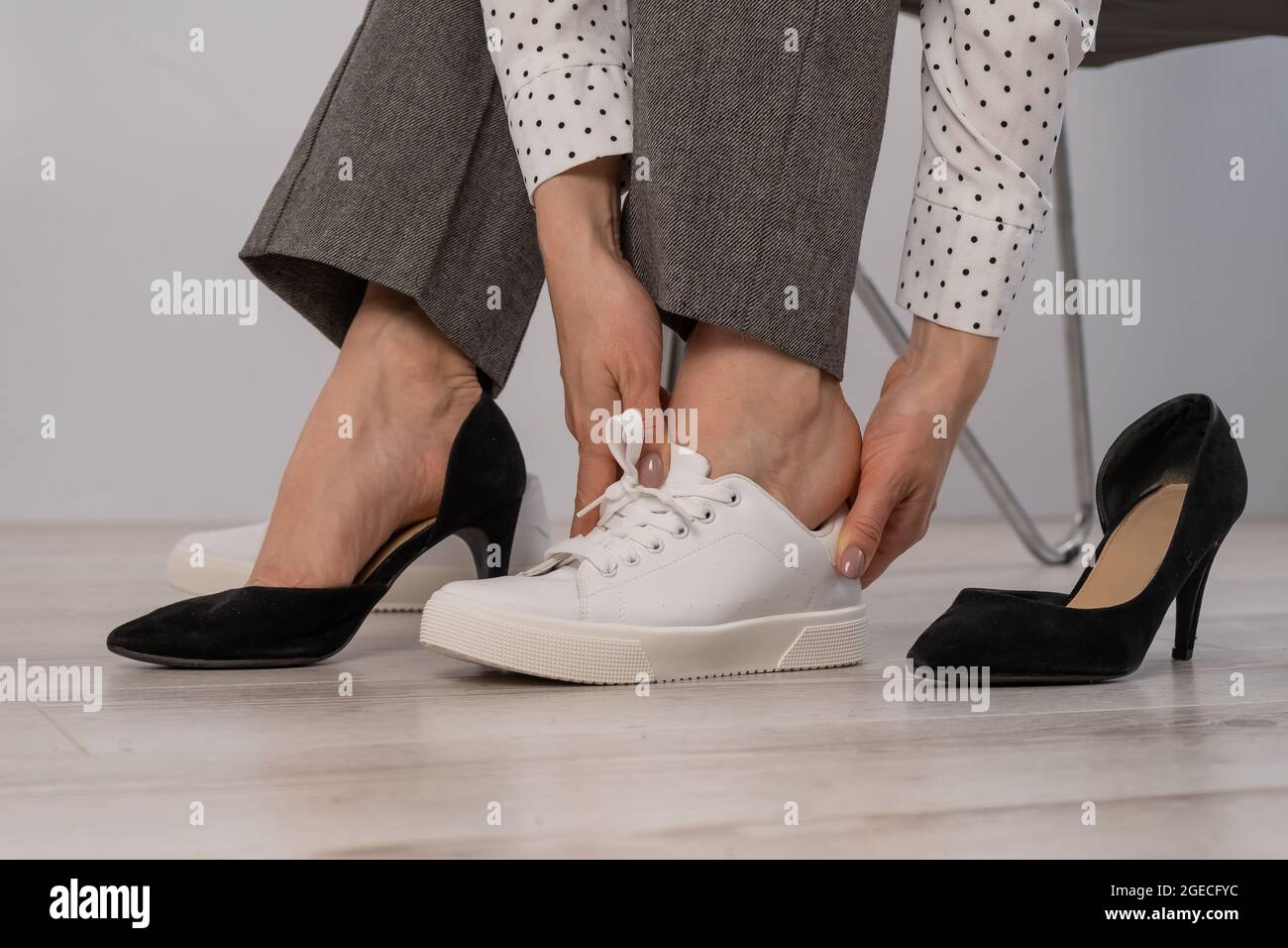 Close-up business woman takes off her shoes puts on white leather ...