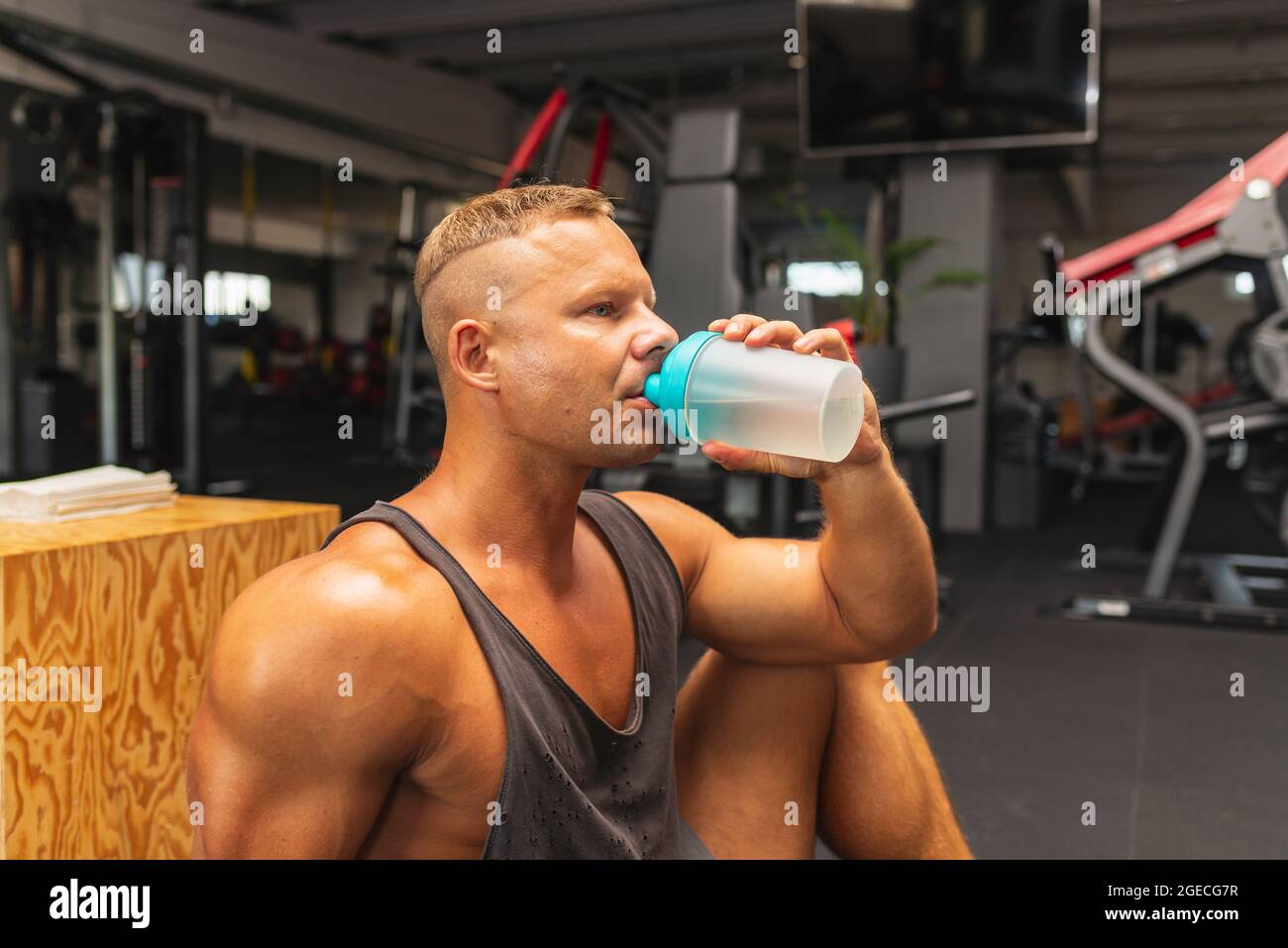 Young caucasian man drinking water after exercise.man in the gym ...