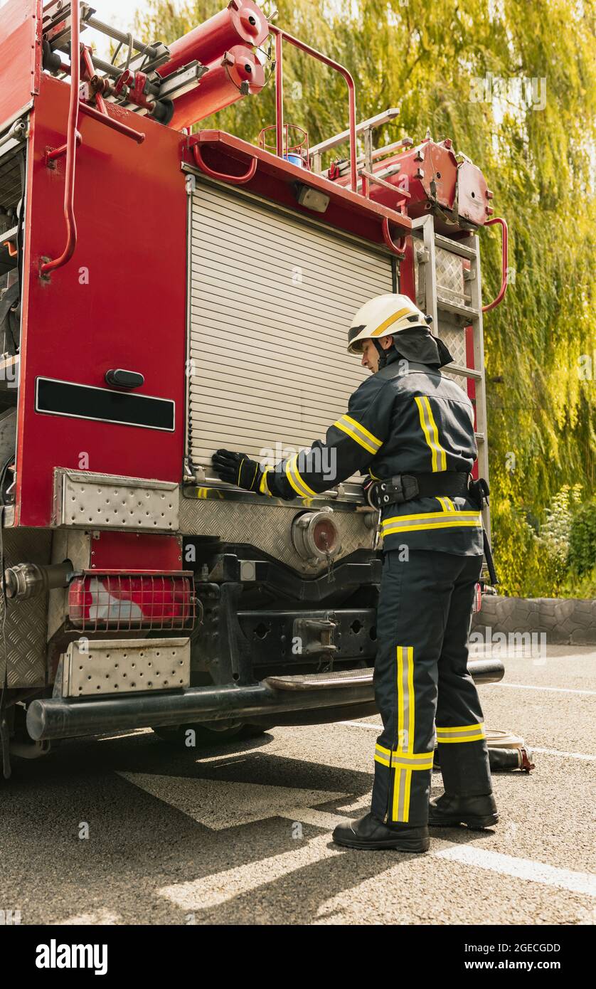 One young male firefighter dressed in uniform with protective helmet ...