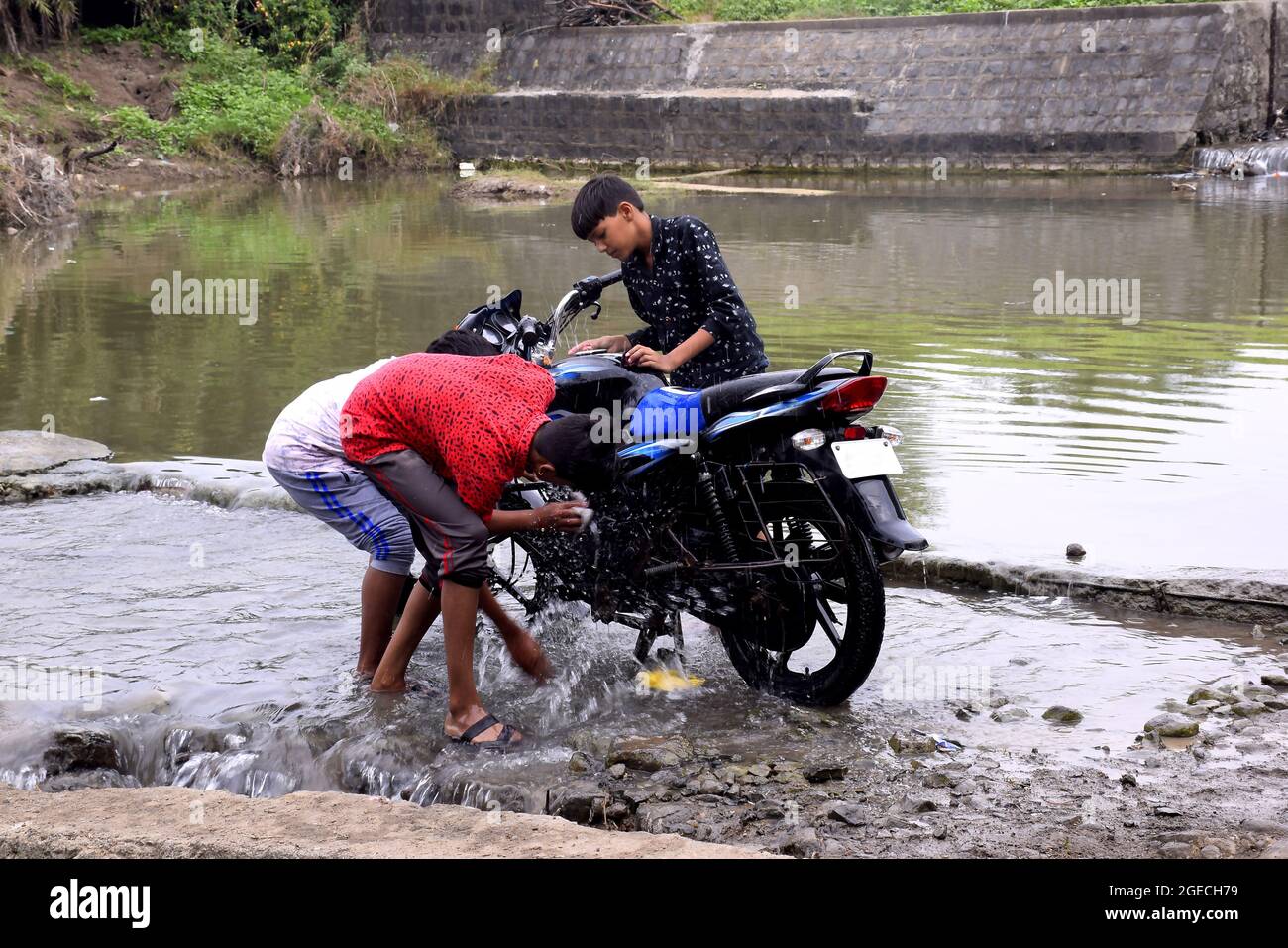 rural children washing bikes with river water, Natural greenery in the ...