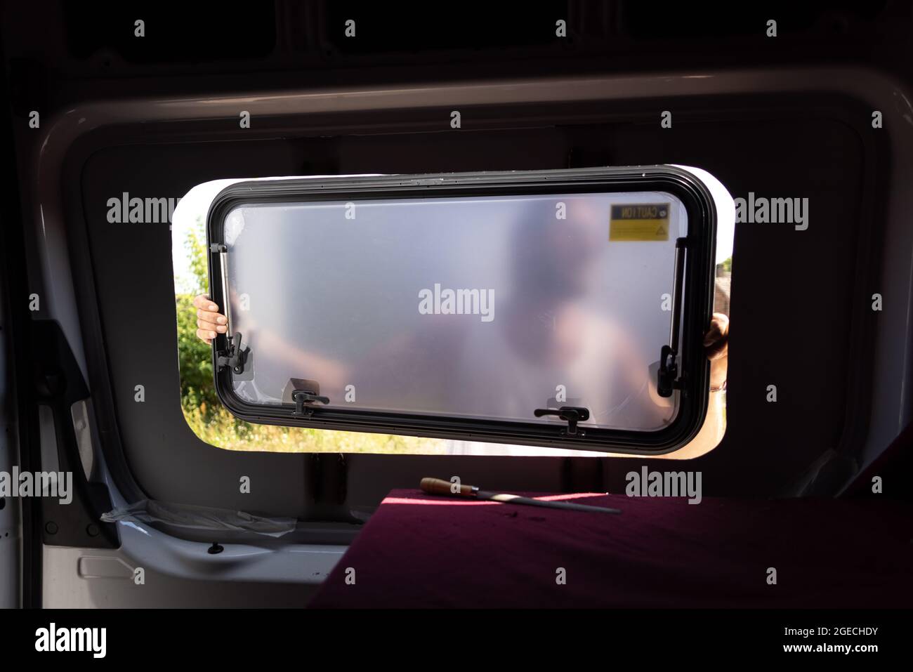 Inside a camper van - man installing a side window Stock Photo - Alamy