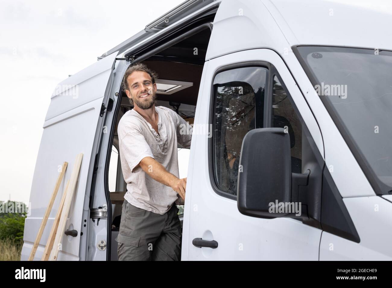 Smiling man standing in the doorway of a van Stock Photo - Alamy