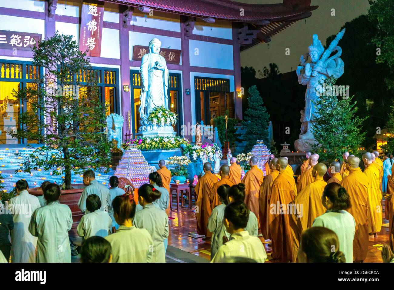 Monks and Buddhists are reverently bowing to Buddha during evening ...
