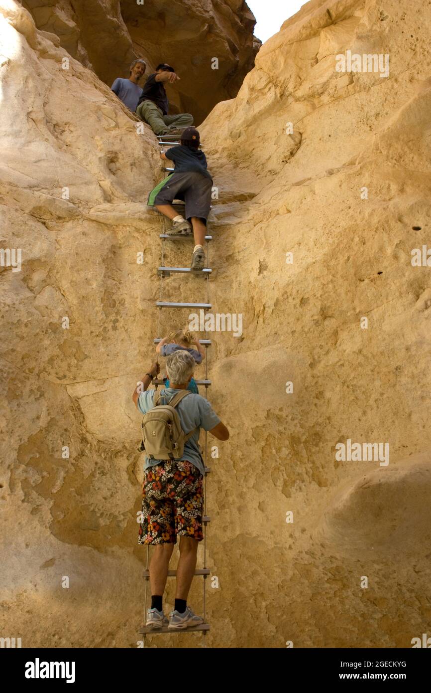 Hiker climbs the rope ladder in a water eroded cave at Barak Stream ...
