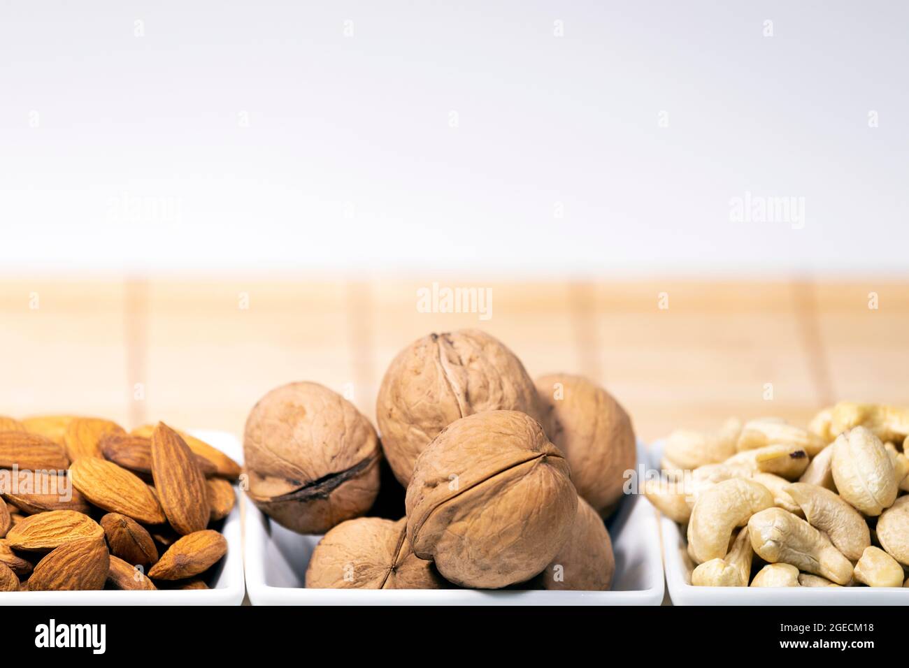 Mix of Nuts, Almond, Cashew, Wallnut in white ceramic bowls on wooden ...