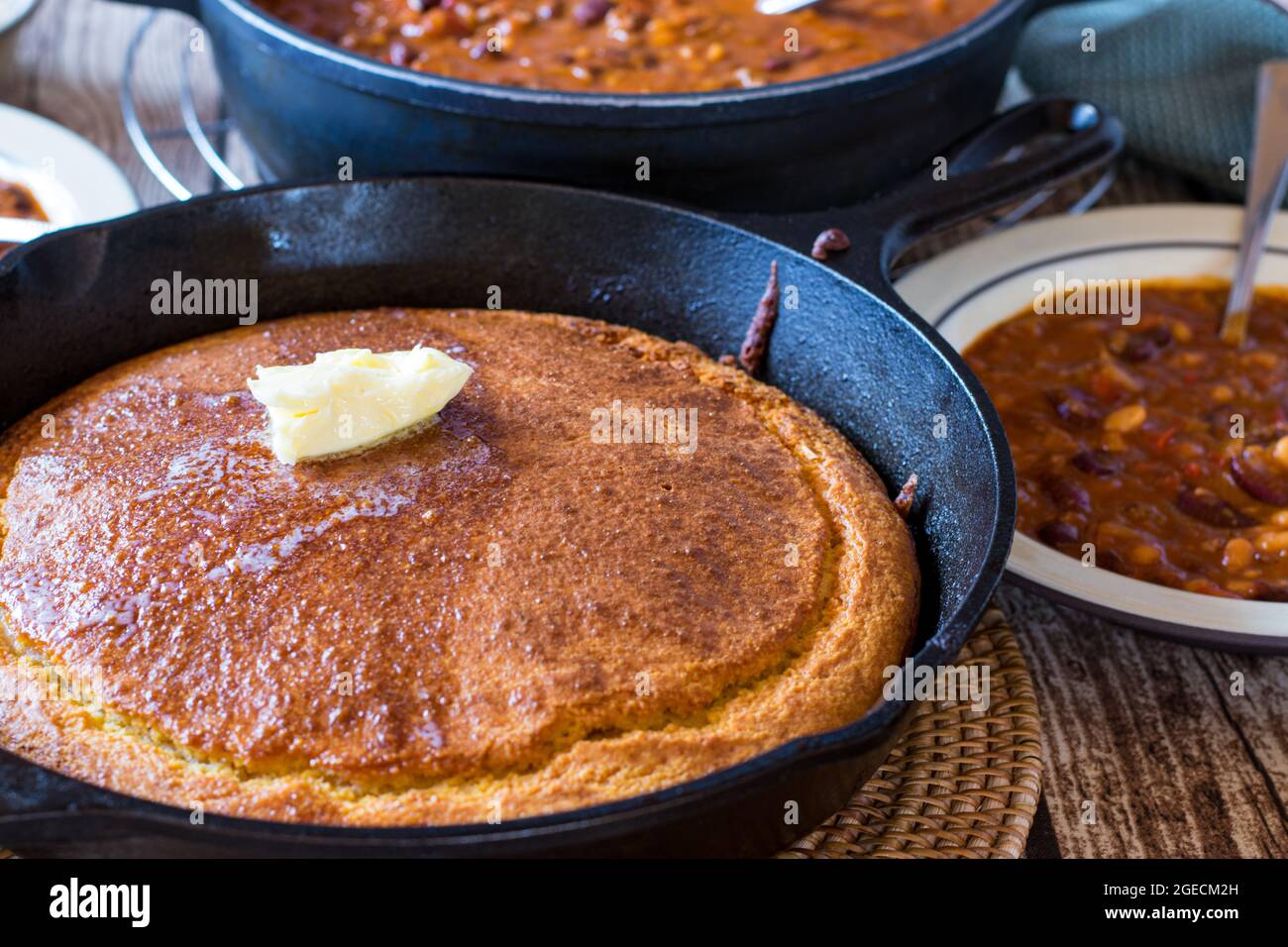 Spicy bean stew with fresh baked cornbread on wooden table Stock Photo ...