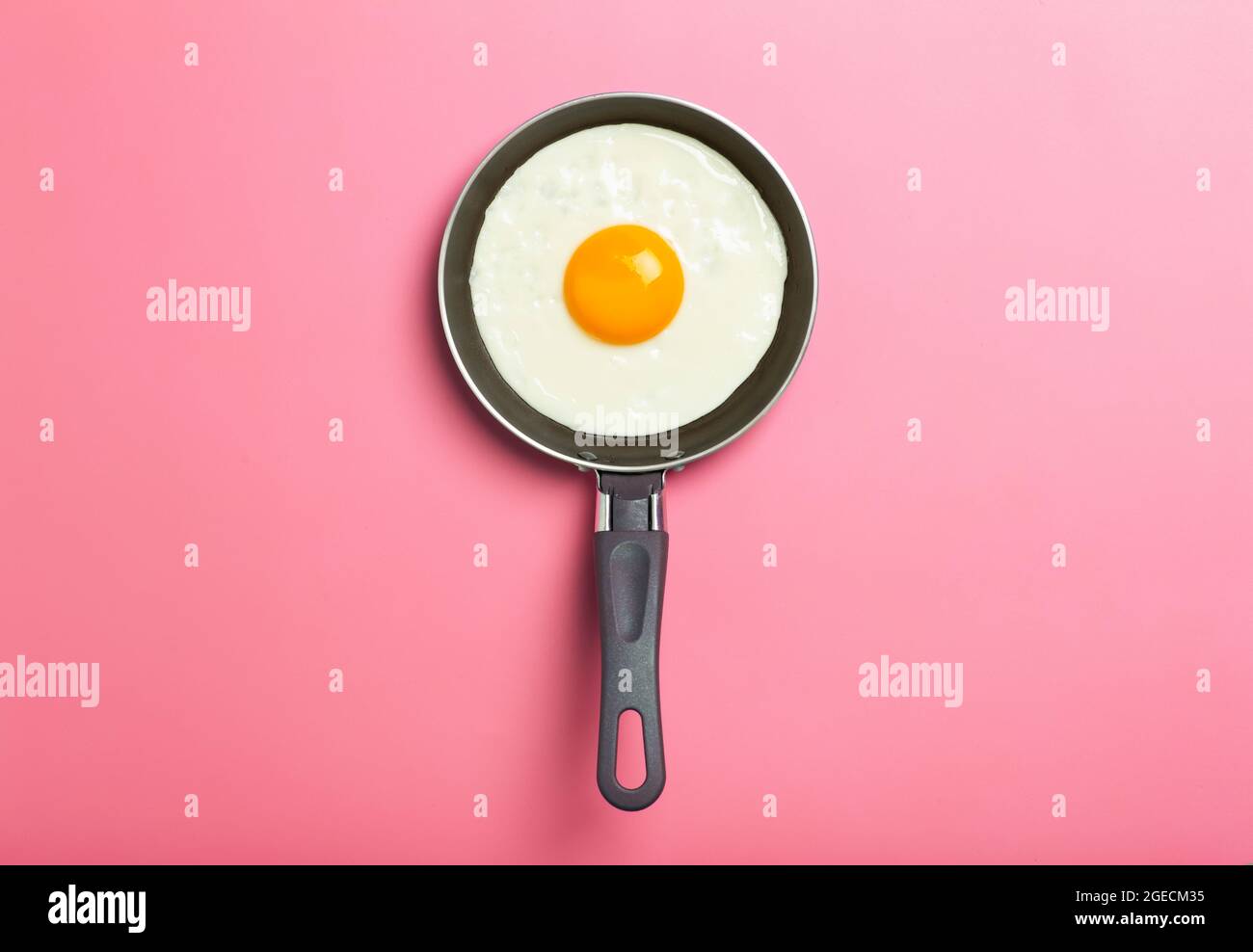 Fried egg is minimal. Fried egg in a frying pan on an empty pink background. Creative breakfast ...