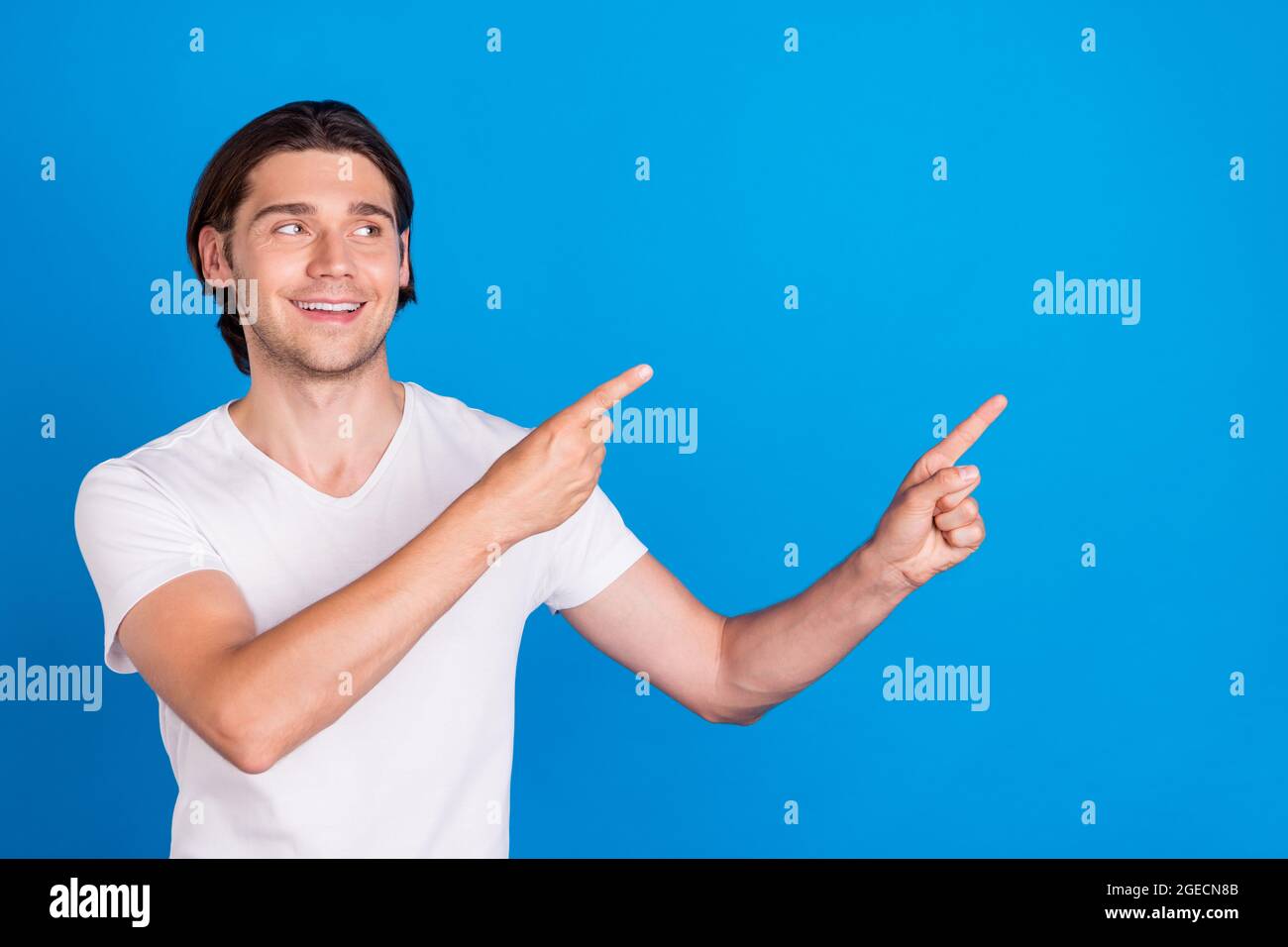 Photo portrait brunet man showing finger empty space advising smiling ...