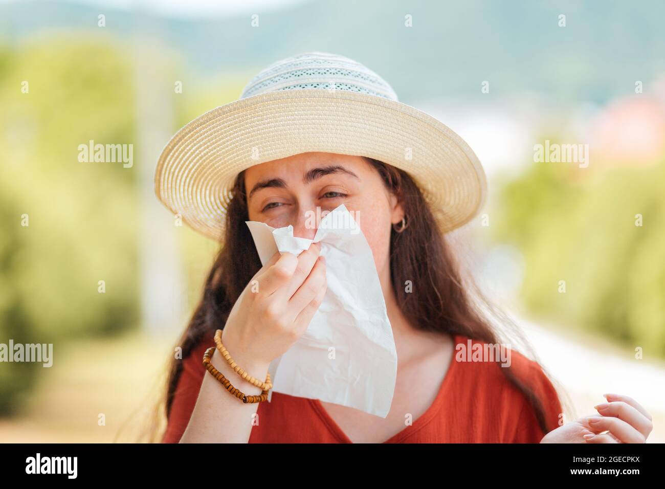 A woman in a straw hat blows her nose in a handkerchief.Outdoor ...