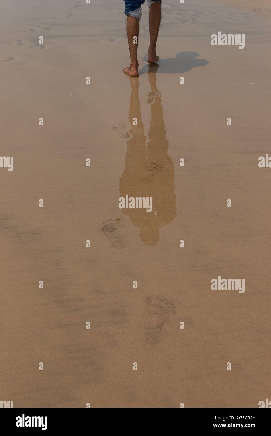 the beautiful reflection of man while walking on the beach Stock Photo ...