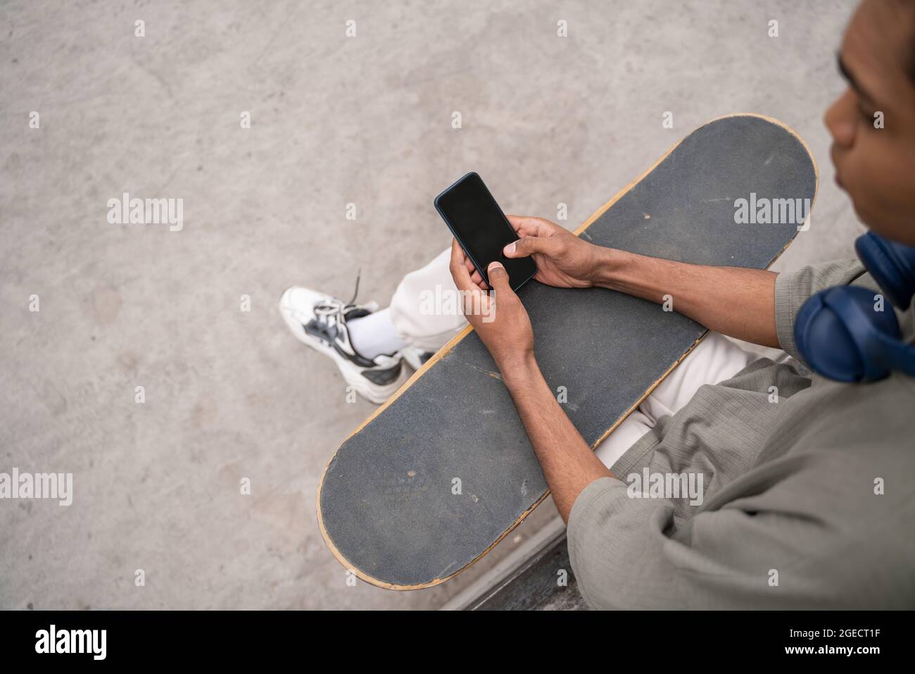 high angle view of cropped african american skater using mobile phone ...