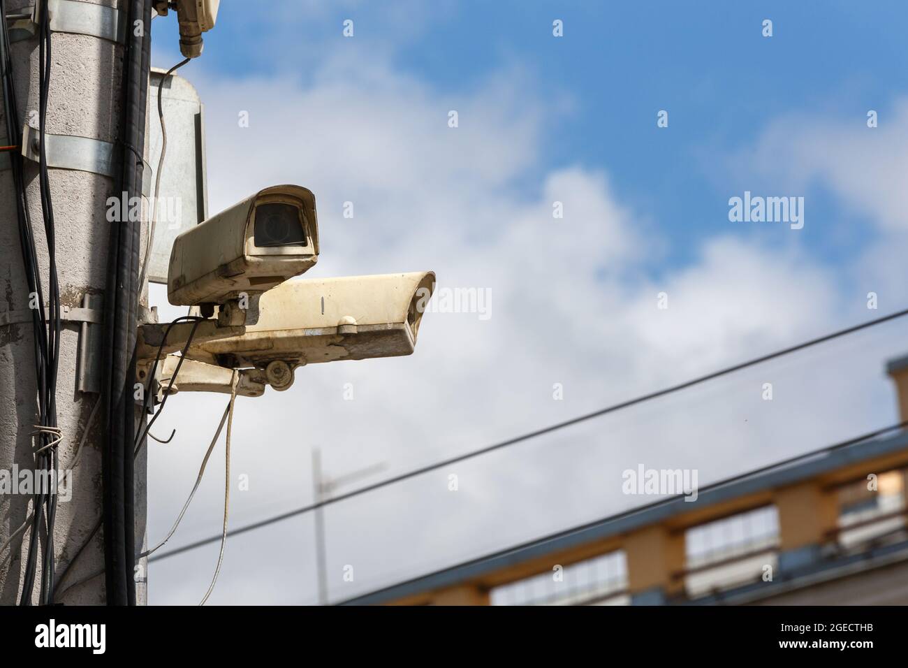 two old security surveillance cameras on street light pole on blue sky ...