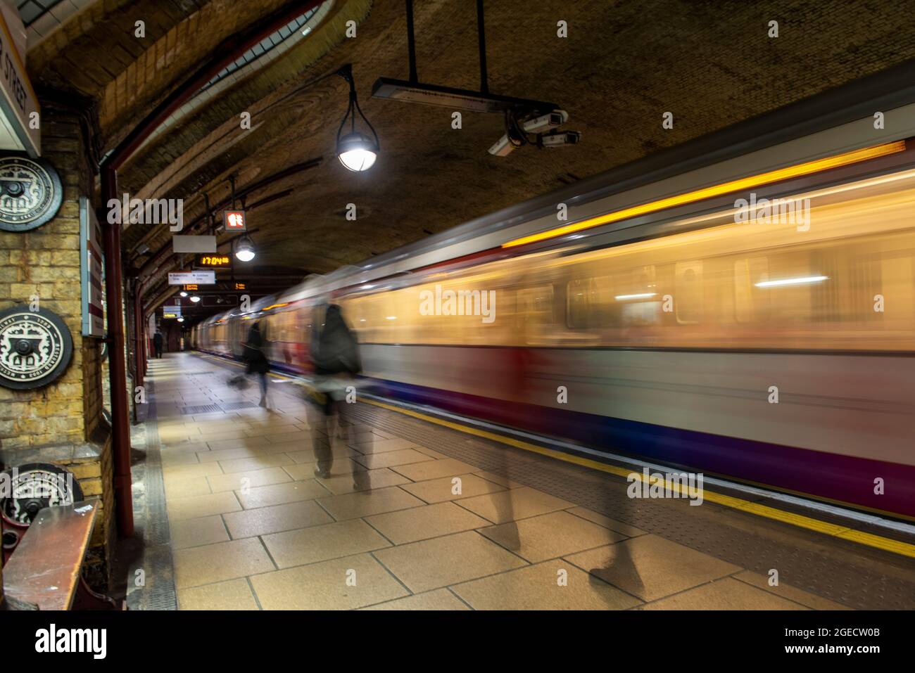 People walking past a moving train at Baker Street Underground Station ...