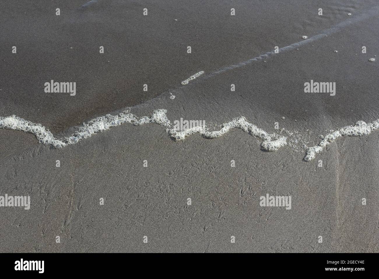 Gray sandy shore with the ocean wave coming towards it viewed from ...