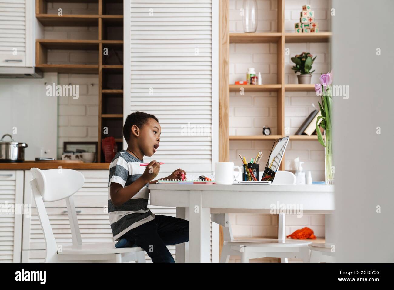 Black boy using laptop and drawing while sitting at home Stock Photo ...