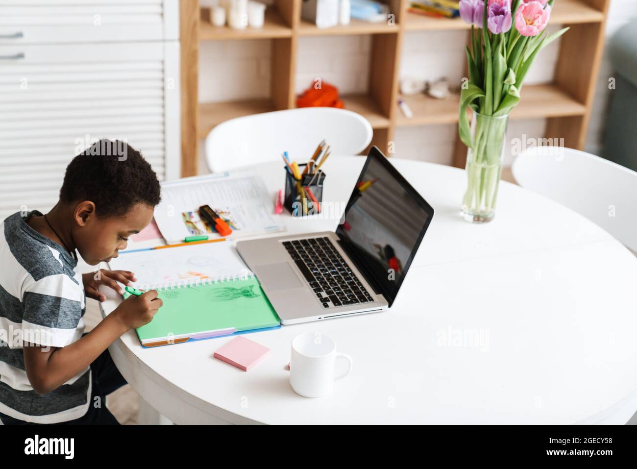 Black boy using laptop and drawing while sitting at home Stock Photo ...