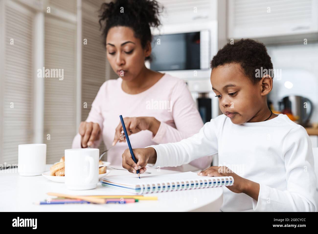 Black boy drawing while having breakfast with her mother at home Stock ...