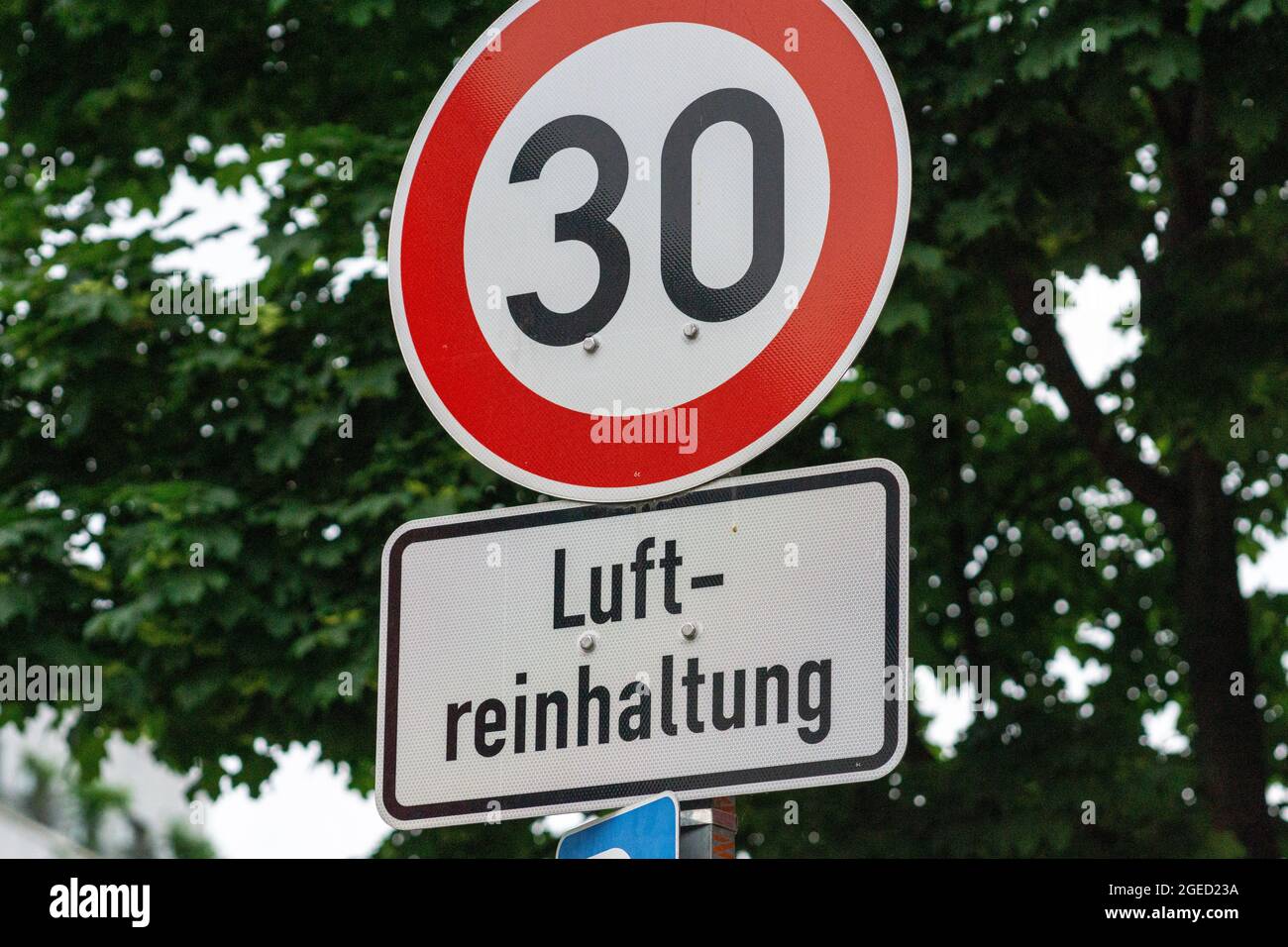Speed limit sign with German writing under it with the blurred trees on ...