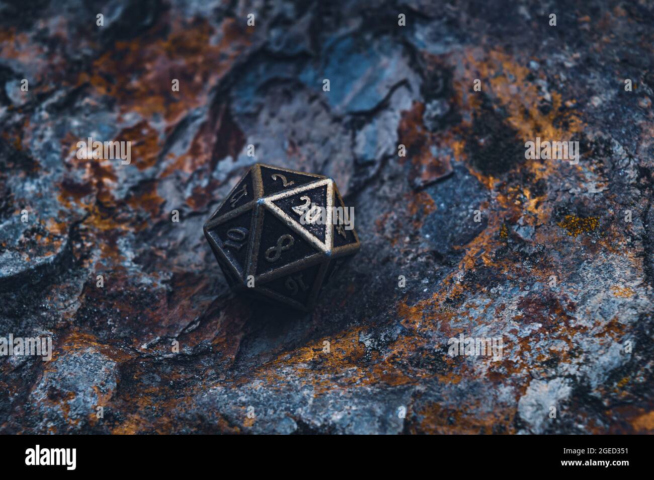 Close-up image of one 20-sided metallic role-playing die on a rough ...