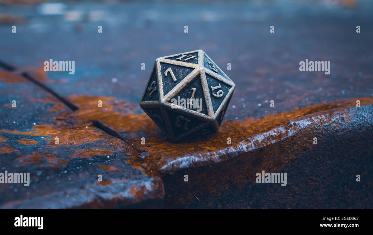 Close-up image of one 20-sided metallic role-playing die on a rusty ...