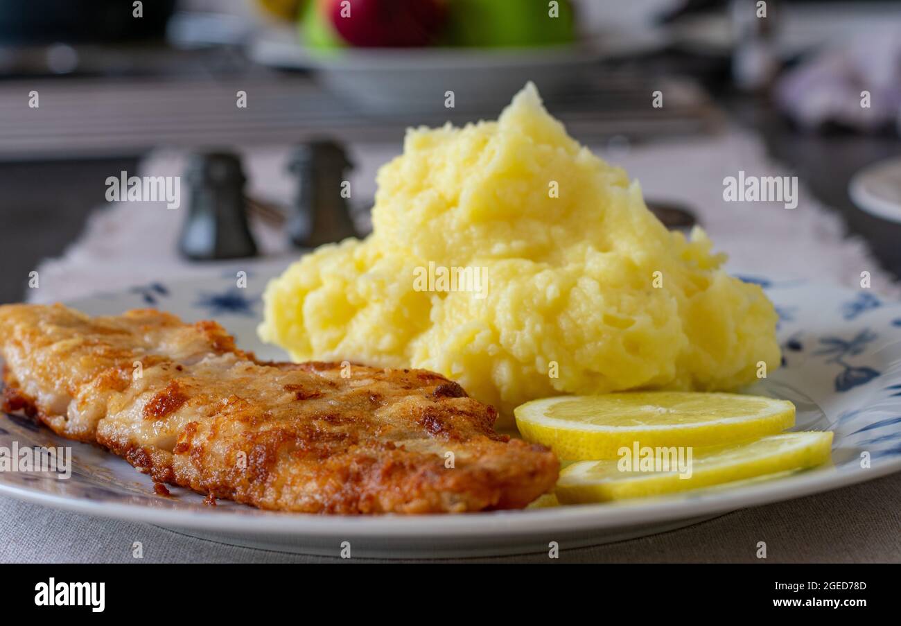 Pan fried breaded fish with mashed potatoes on a plate on kitchen table ...