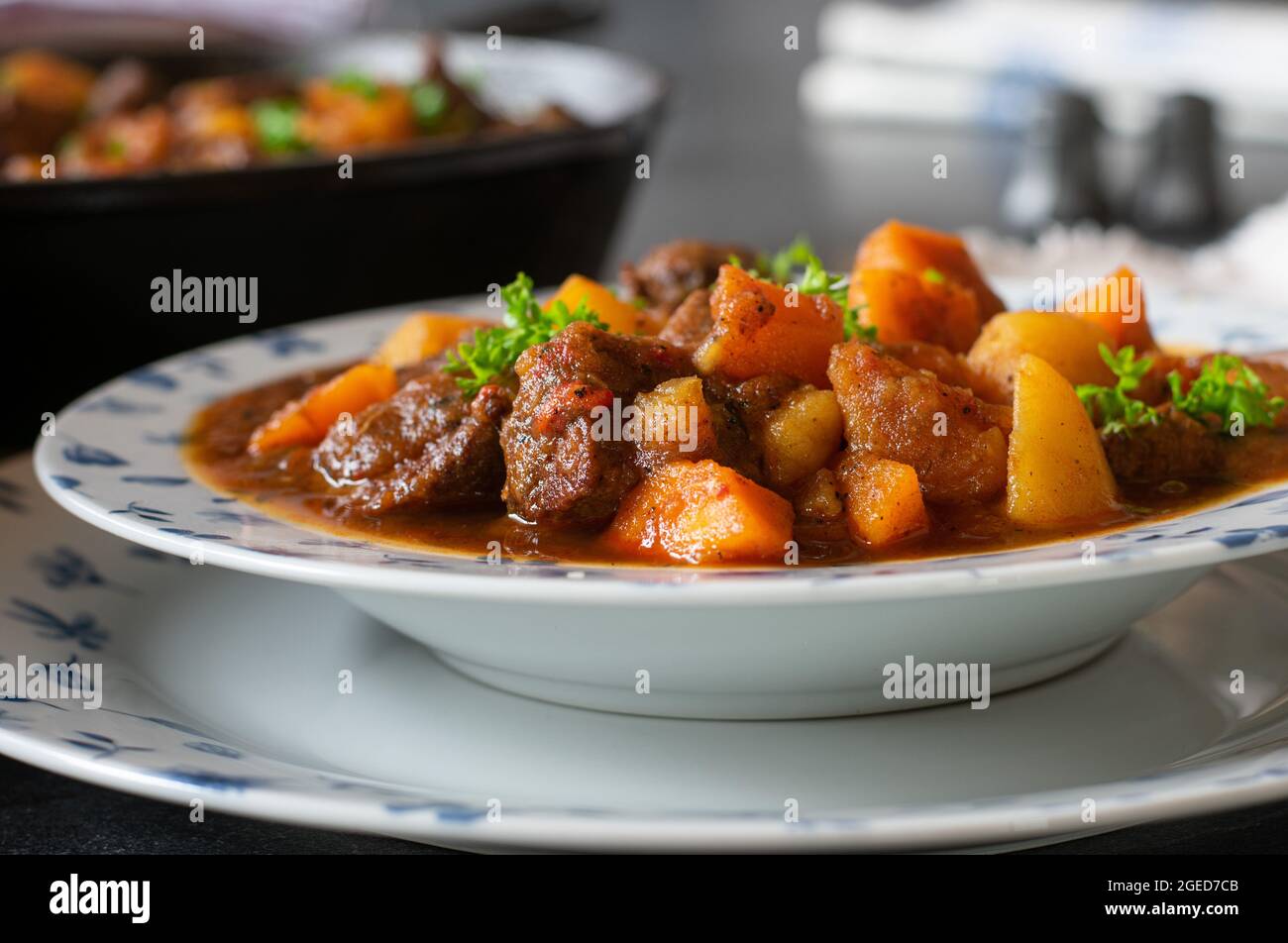 Beef stew with carrots and potatoes on a deep plate on kitchen table ...