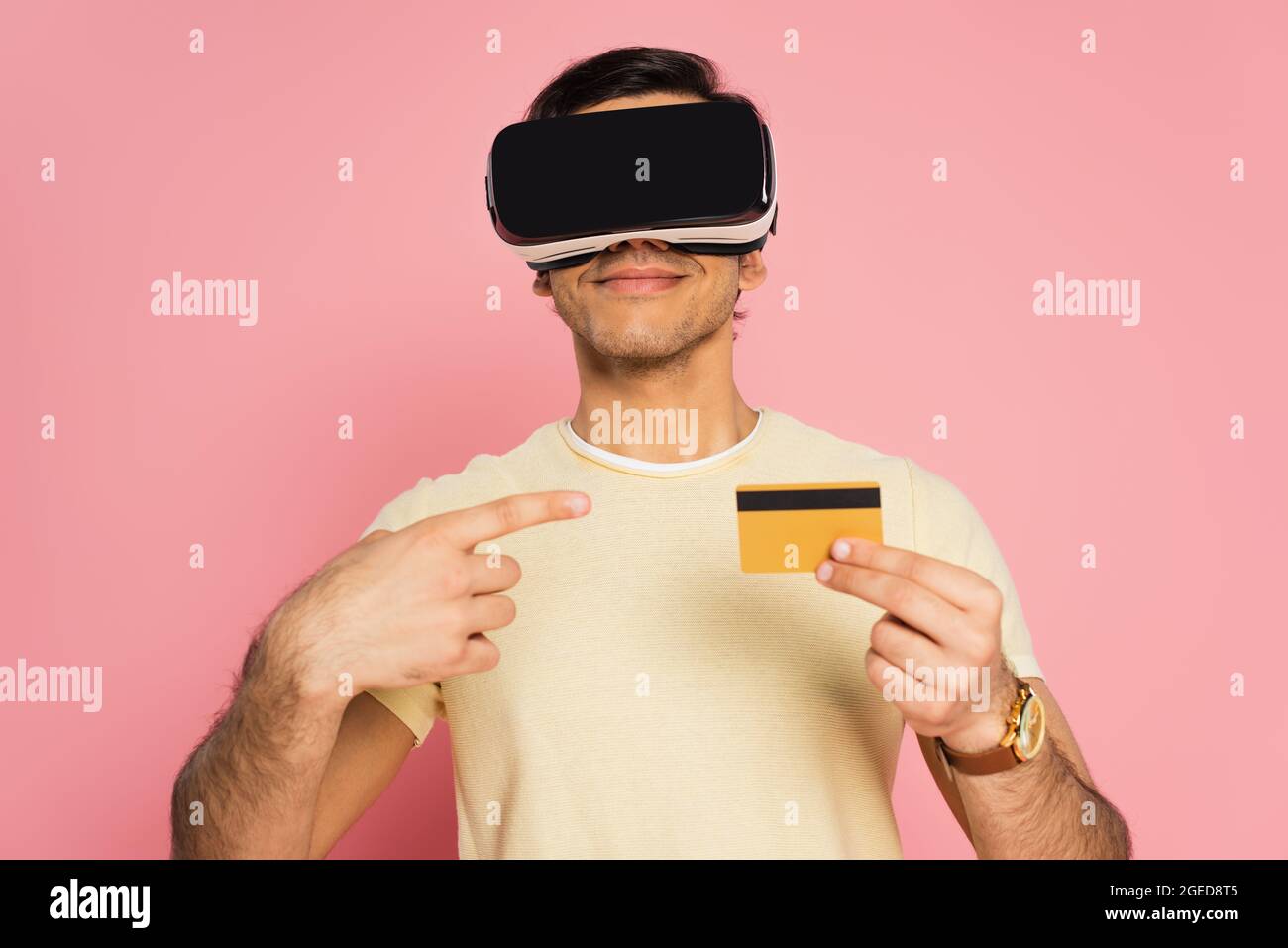 cheerful man in vr headset pointing with finger at credit card isolated ...