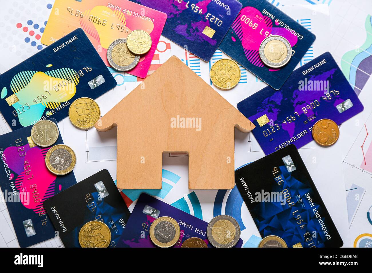 House figure with coins and credit cards on charts Stock Photo - Alamy