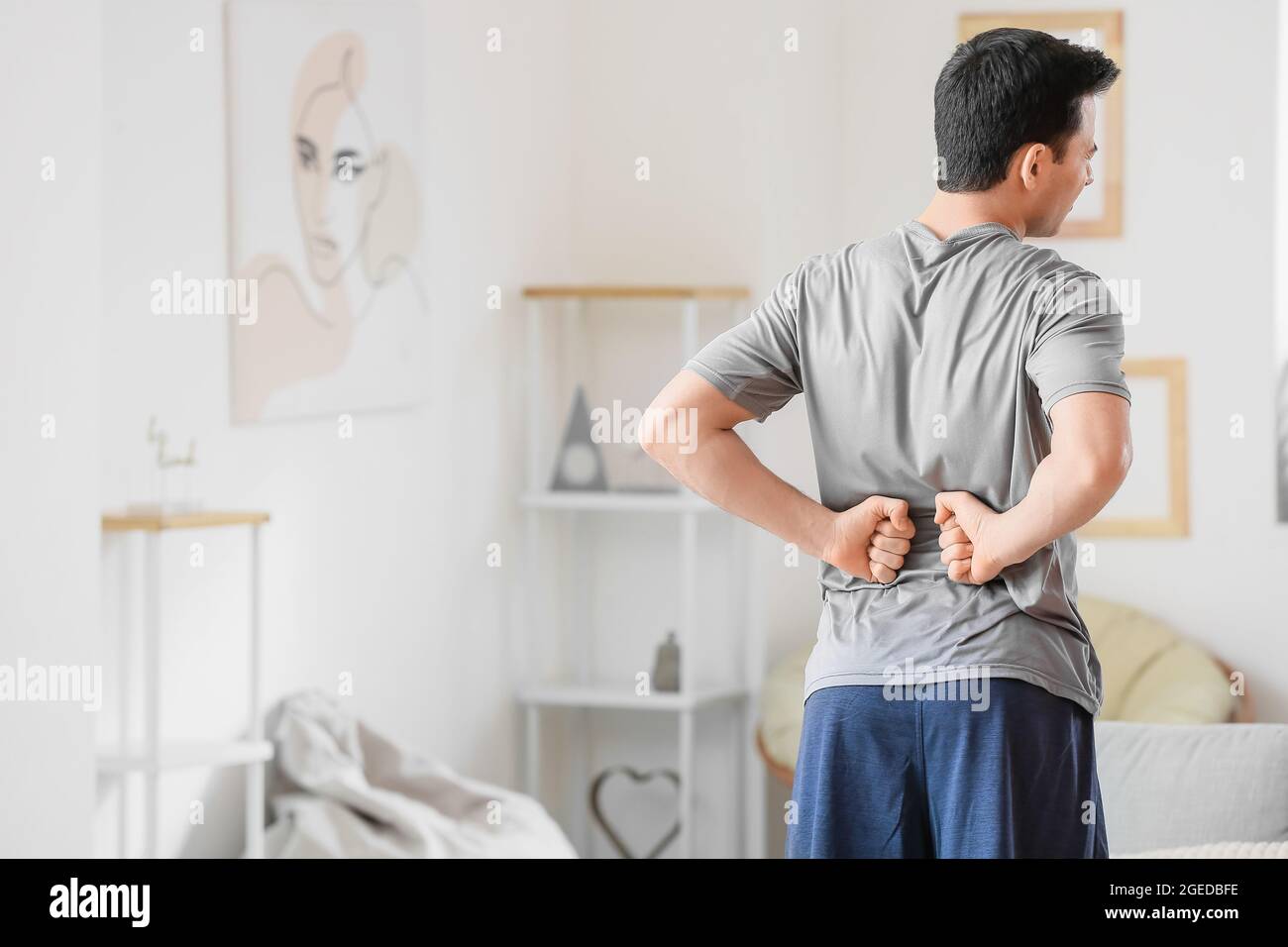 Young man suffering from back pain at home Stock Photo - Alamy