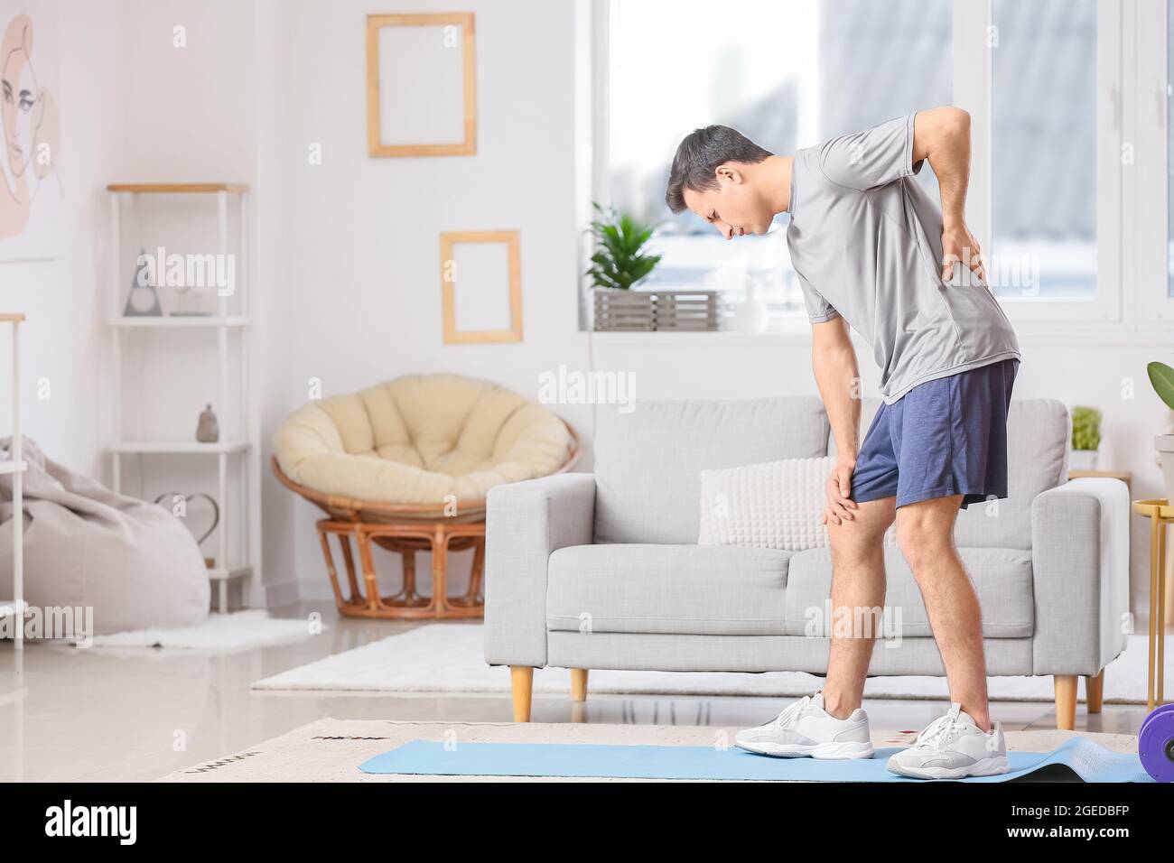 Young man suffering from back pain at home Stock Photo - Alamy