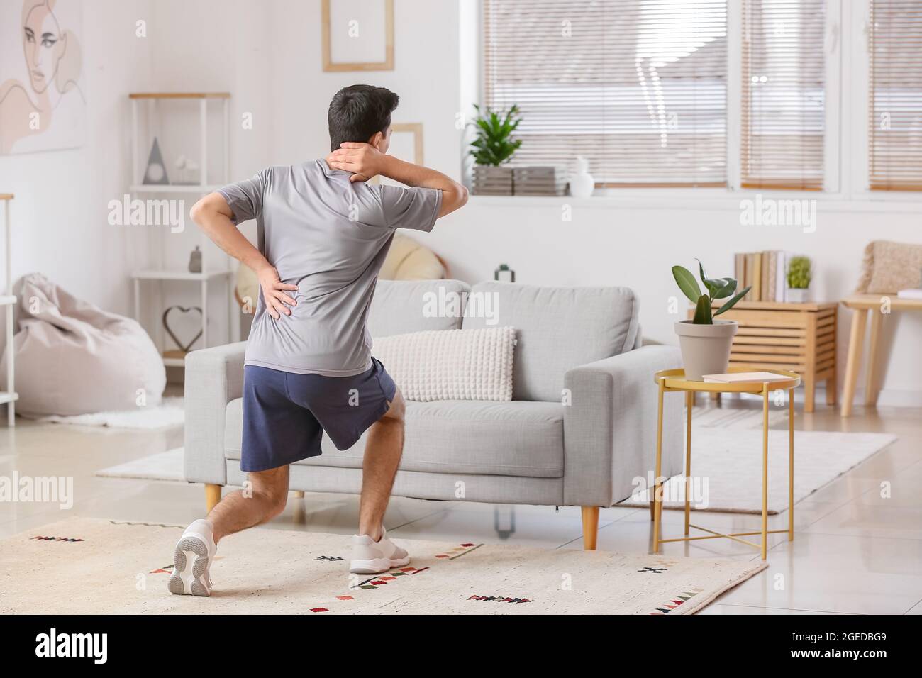 Young man suffering from back pain at home Stock Photo - Alamy