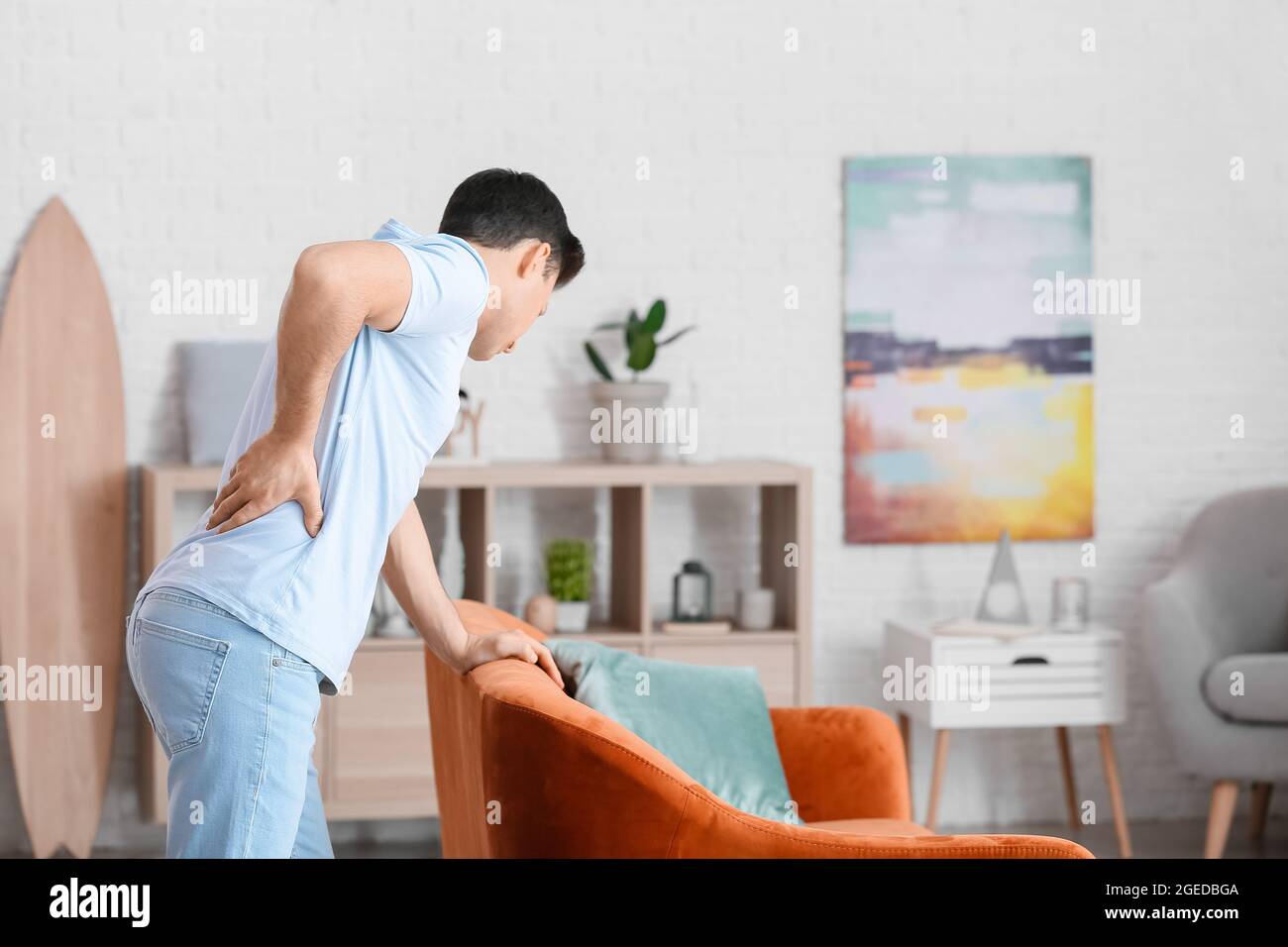 Young man suffering from back pain at home Stock Photo - Alamy