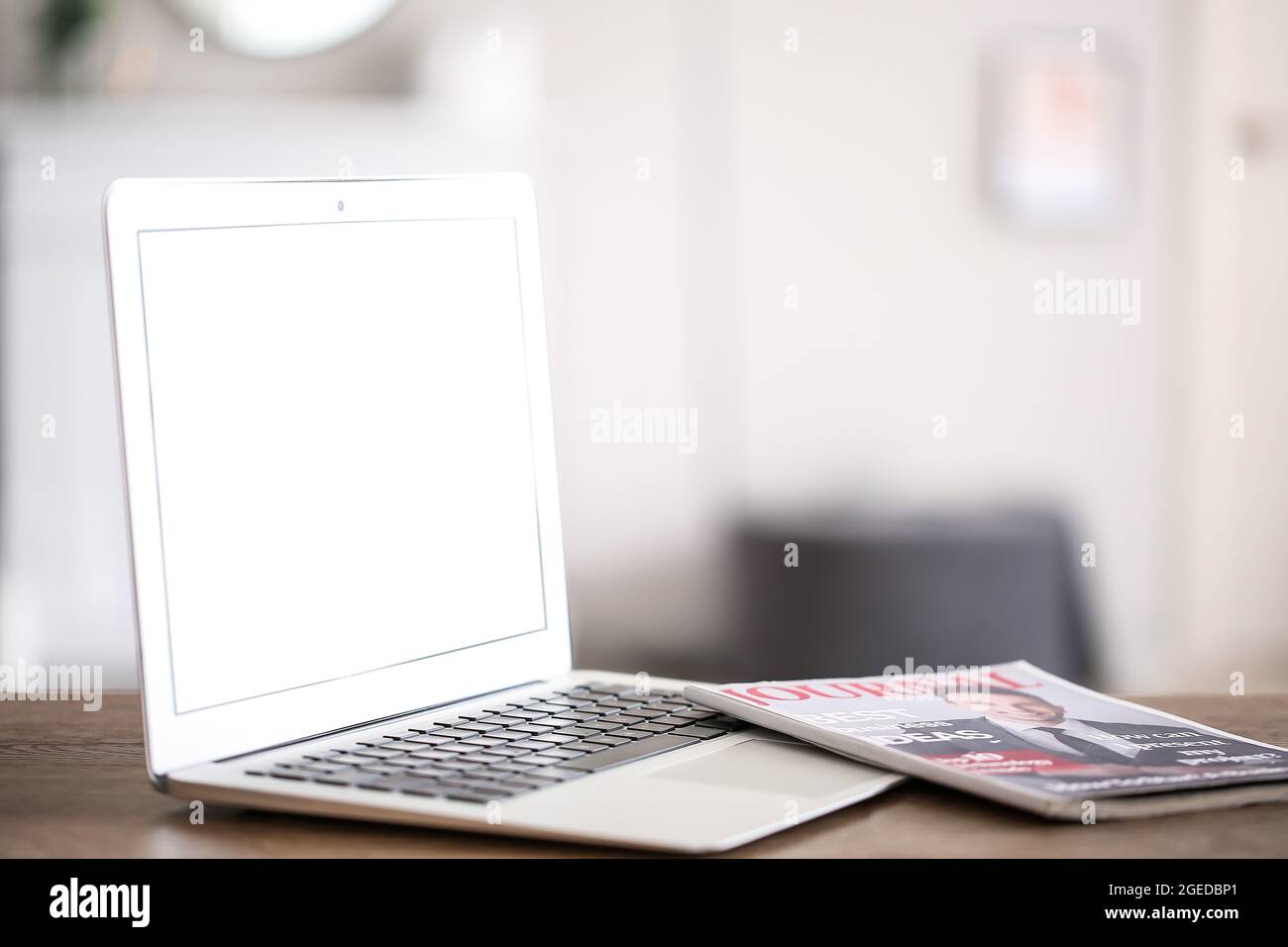 Modern laptop with magazine on table in room Stock Photo - Alamy
