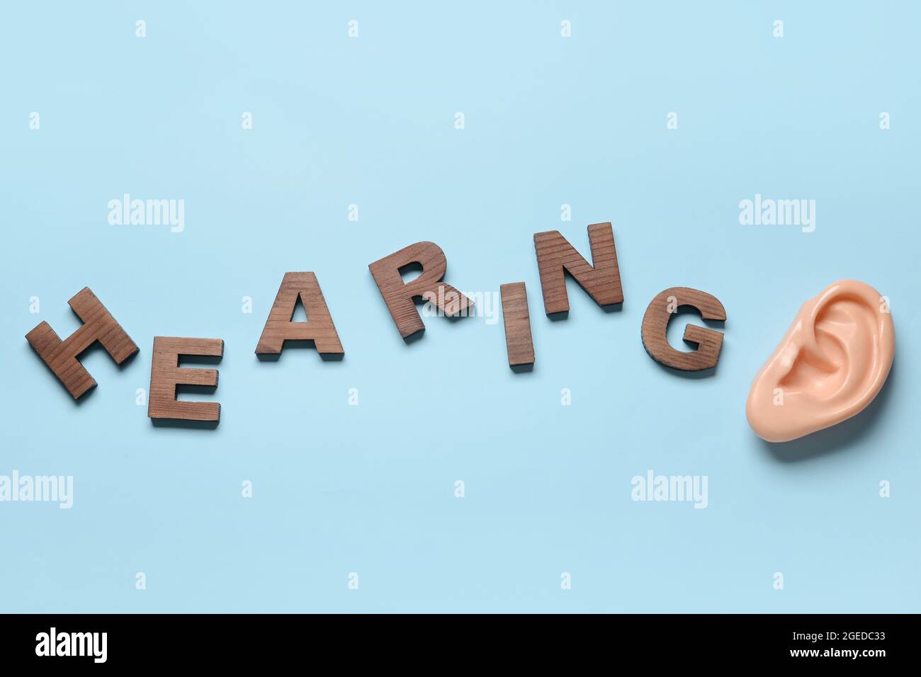 Word HEARING and model of ear on color background Stock Photo - Alamy