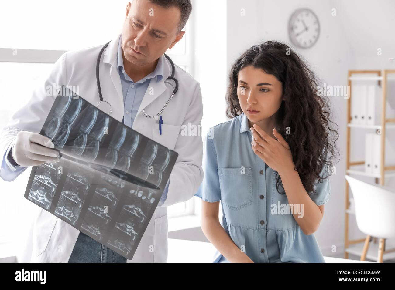 Mature doctor showing x-ray scan to patient in clinic Stock Photo - Alamy