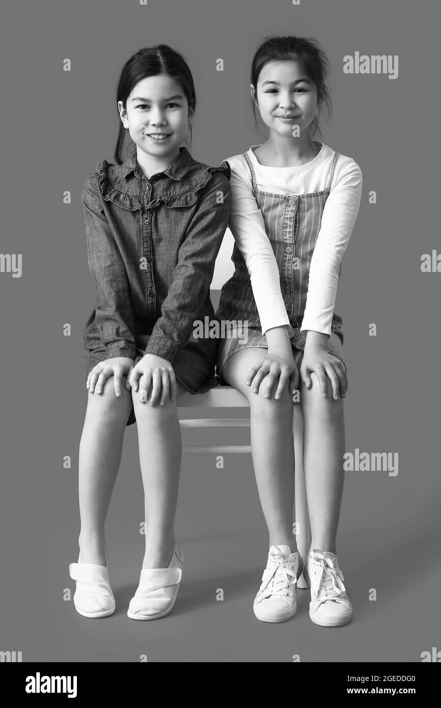 Black and white portrait of cute little sisters on grey background ...