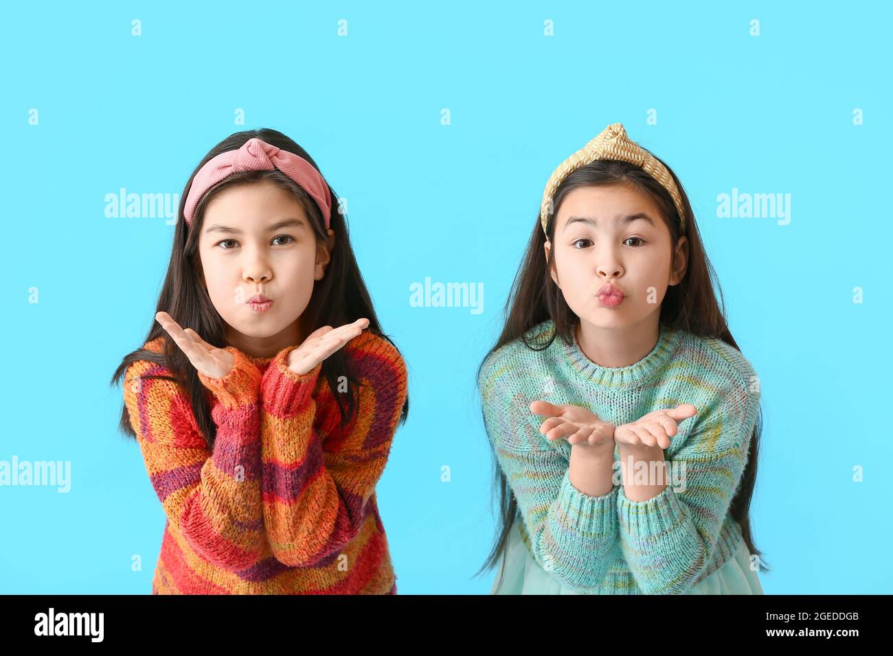 Cute little sisters blowing cheeks on color background Stock Photo - Alamy