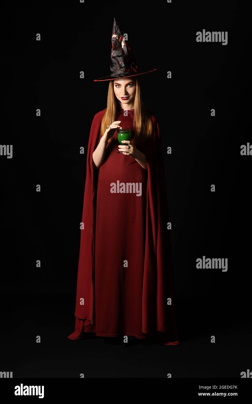 Young witch with potion on dark background Stock Photo - Alamy