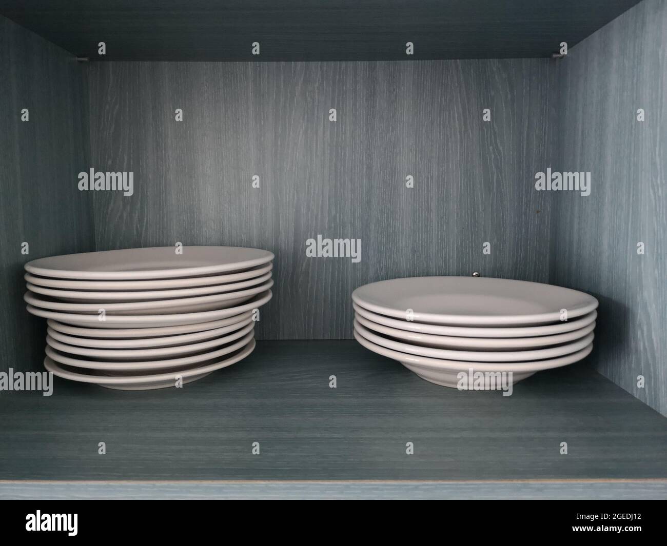 Ceramic stacked plates in a blue cupboard Stock Photo - Alamy