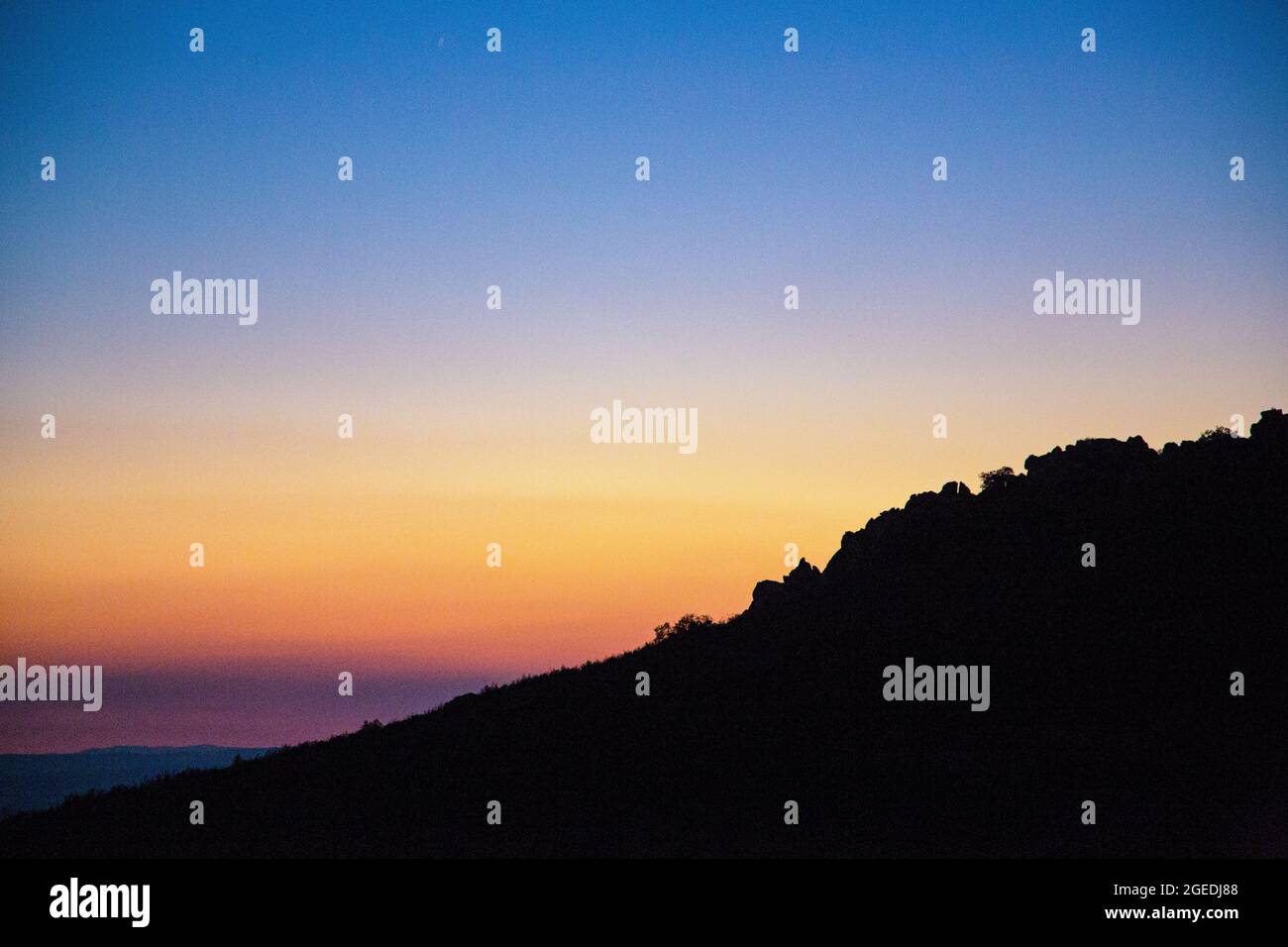 Orange sunset and backlit mountain profile Stock Photo - Alamy
