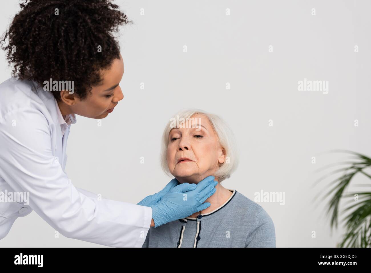 African american doctor checking neck of senior patient Stock Photo - Alamy