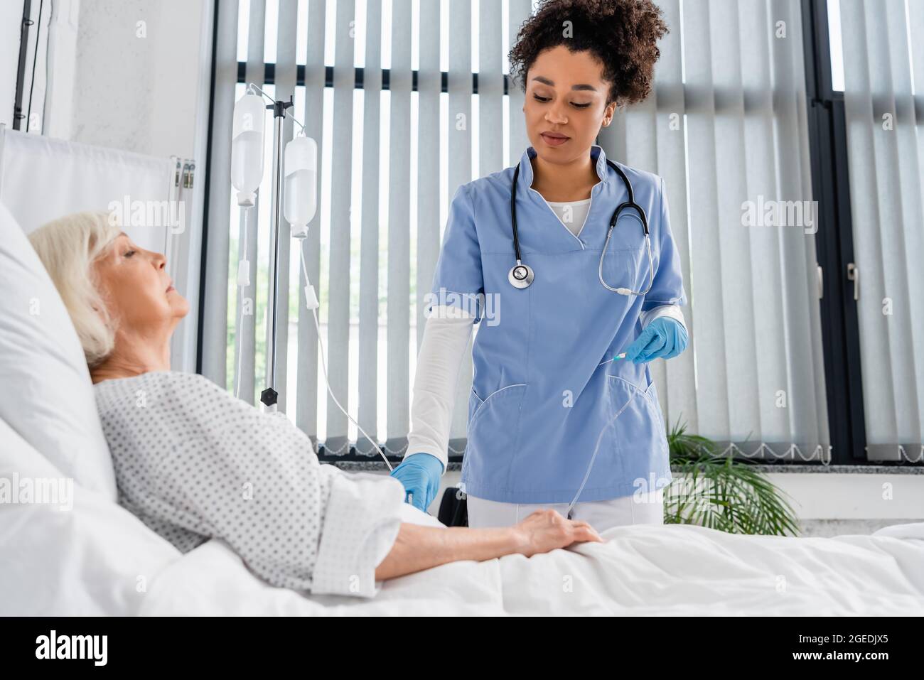 African american nurse holding catheter near elderly patient in clinic ...
