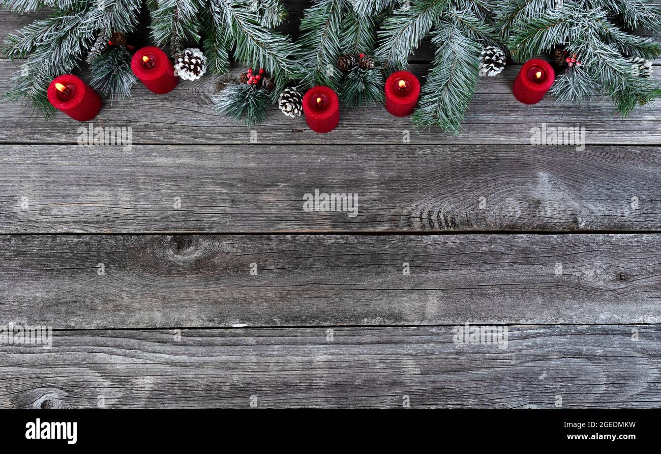 Snow covered evergreen branches with bright red burning candles, on ...