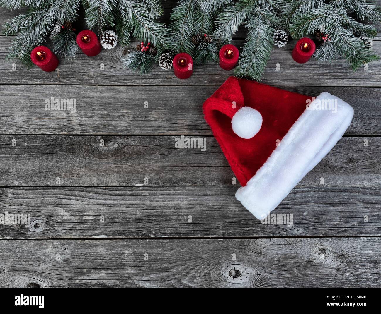 Snow covered evergreen branches with bright red burning candles and a ...