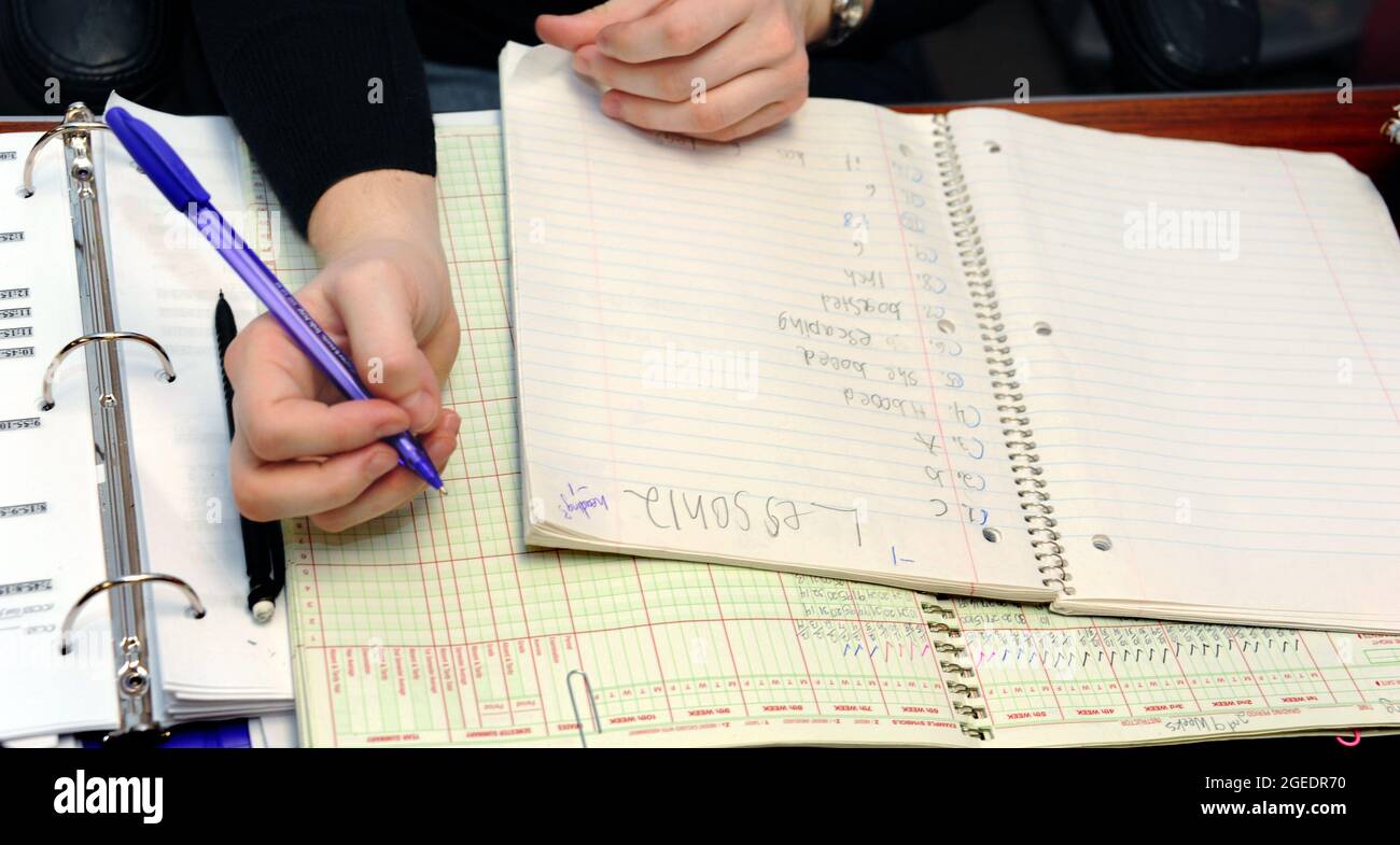 Teacher grades papers and records it in her grade book. She is holding ...