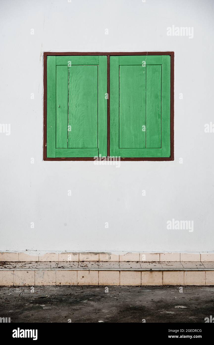 green wood window frame on white wall by walkway Stock Photo - Alamy