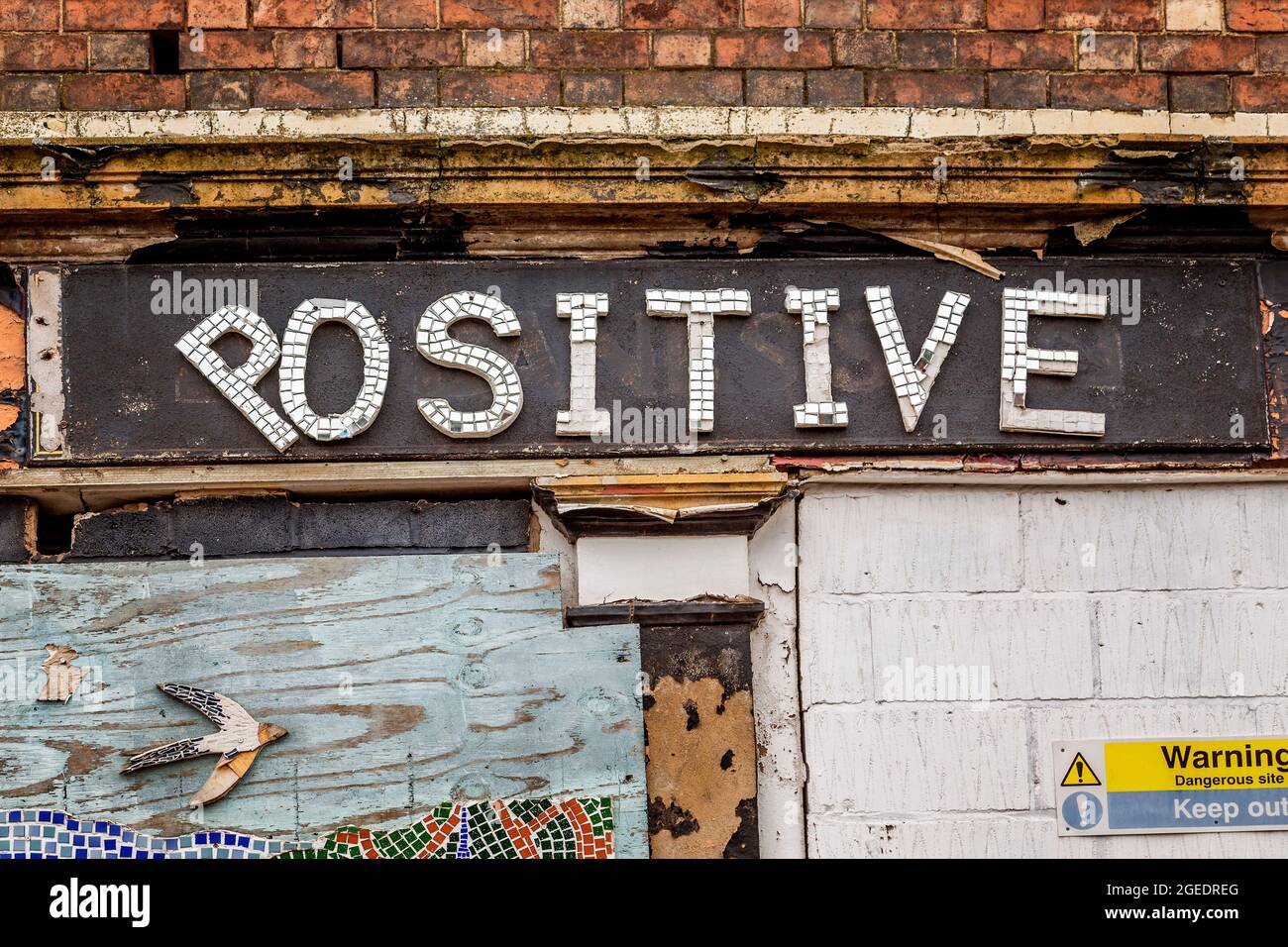 A boarded up shop front ironically displays the word positive in it's ...