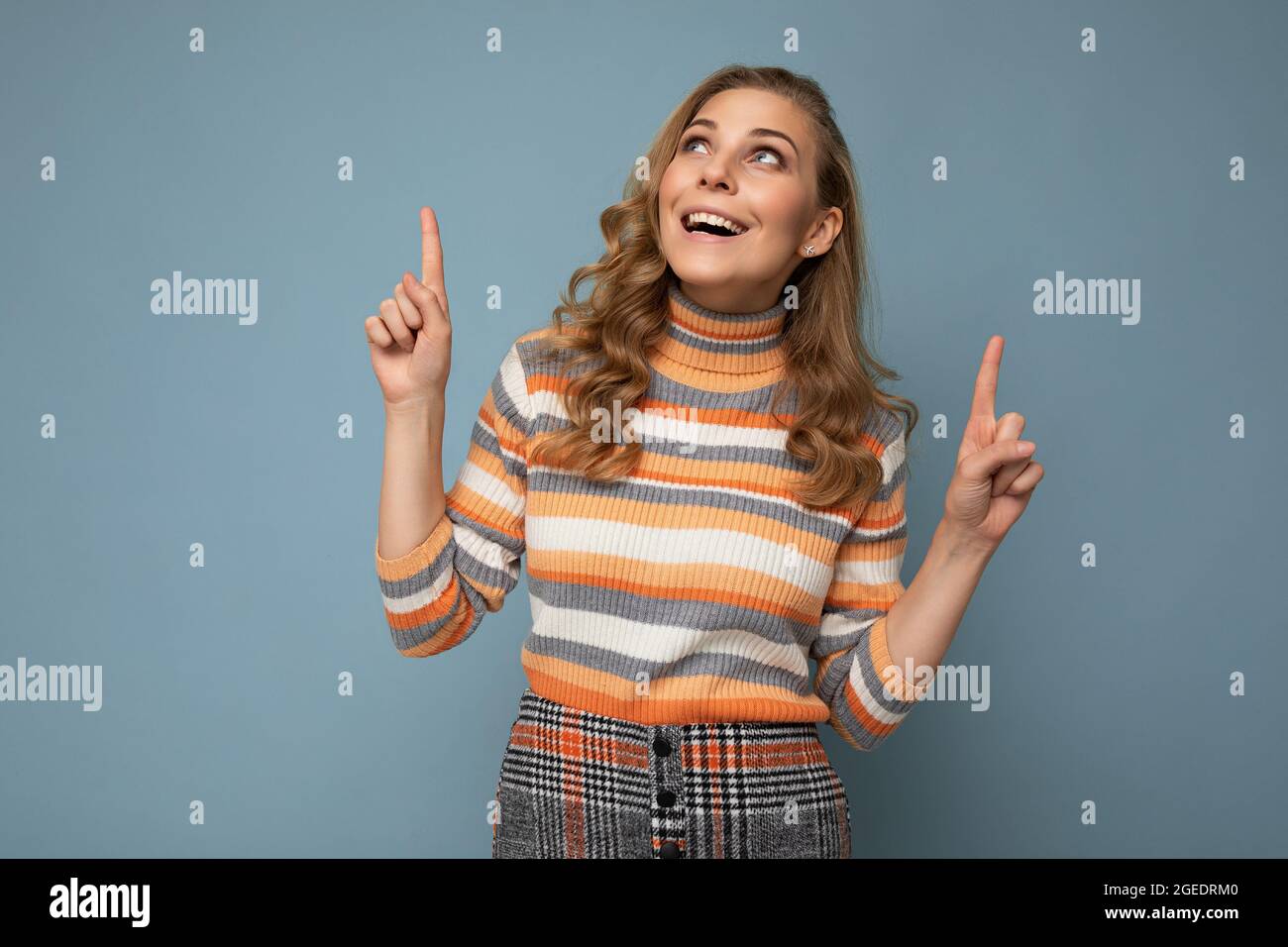 Photo of pretty astonished young woman pointing fingers up at copyspace ...