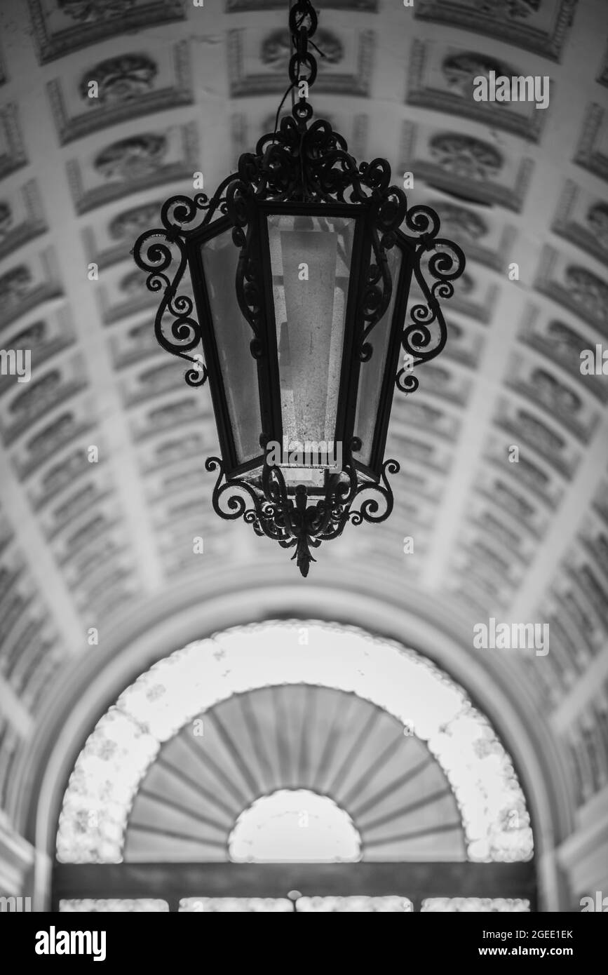 Vertical grayscale shot of a gallery ceiling with an ornamental light ...